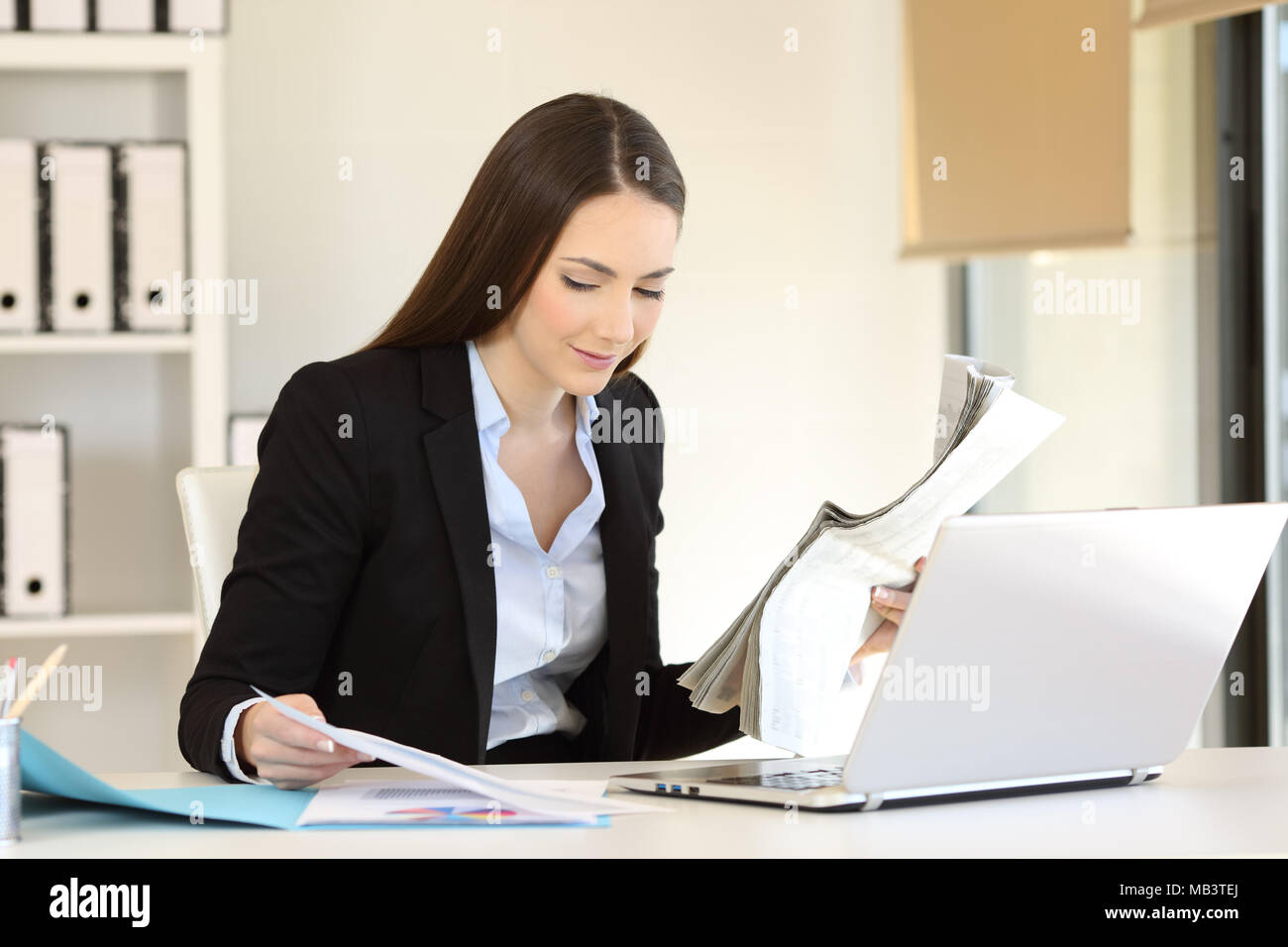 Office worker checking news and documents online with a laptop and a ...