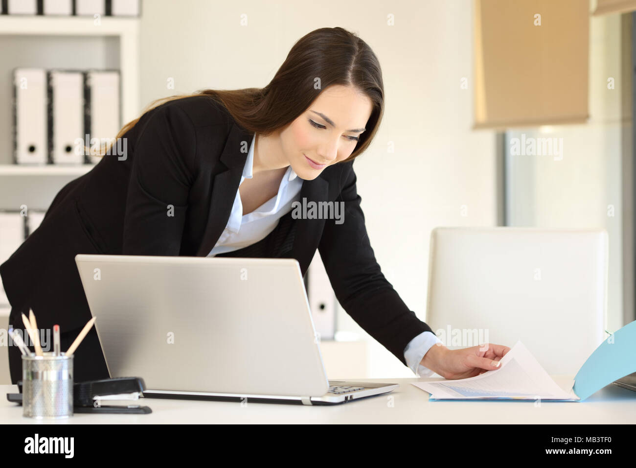 Office worker working comparing documents online with a laptop on a ...