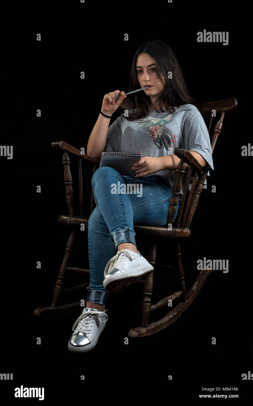 teenage girl writing or drowing whit a pencil in a rocking chair, on ...