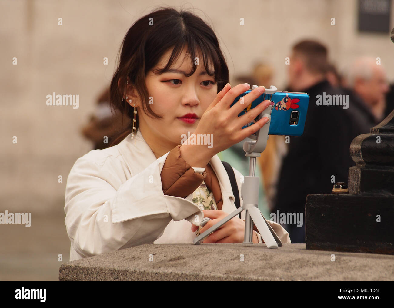 A young woman setting up her smartphone on a small tripod on a concrete ...