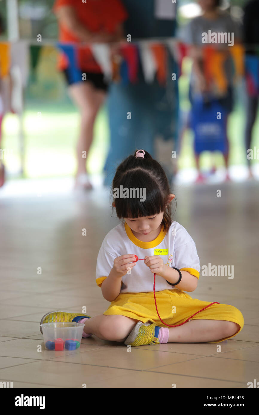 Children are in the game of threading the beads during their ...