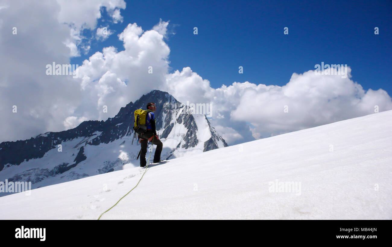 male mountain climber looks towards the summit and his goal while ...
