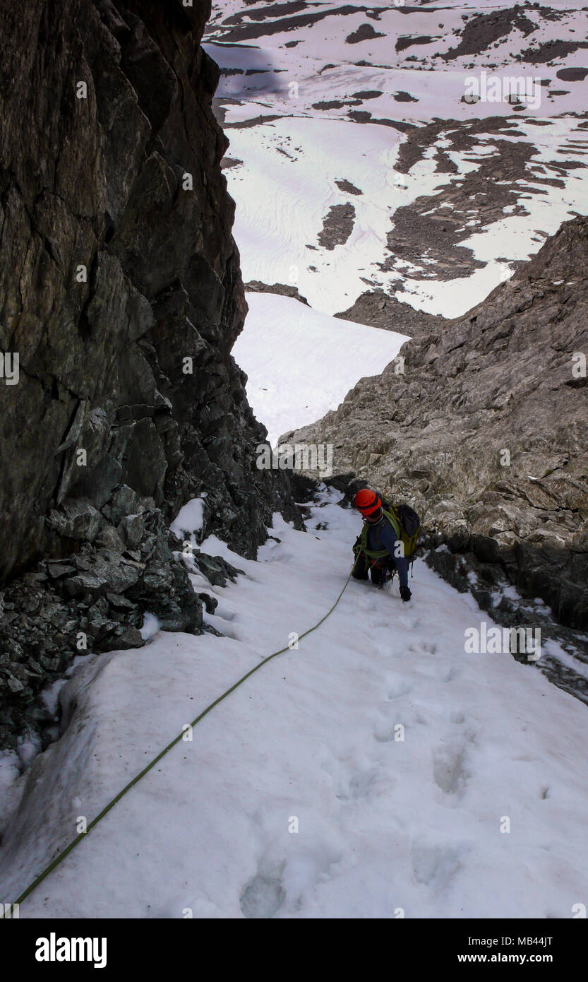 male mountain climber in a very steep and narrow gully on a rope and ...