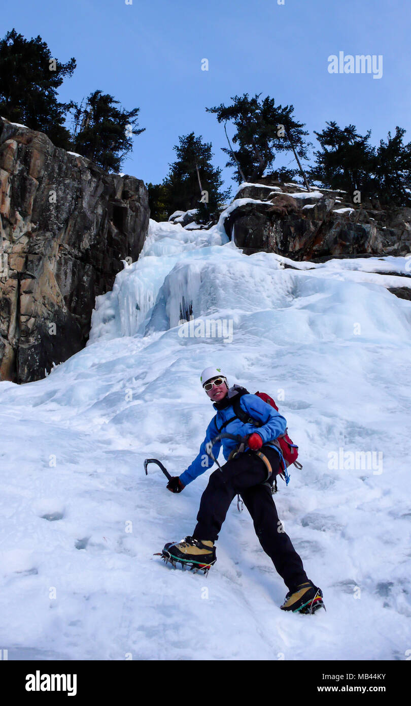 male ice climber in a blue jacket on a gorgeous frozen waterfall ...