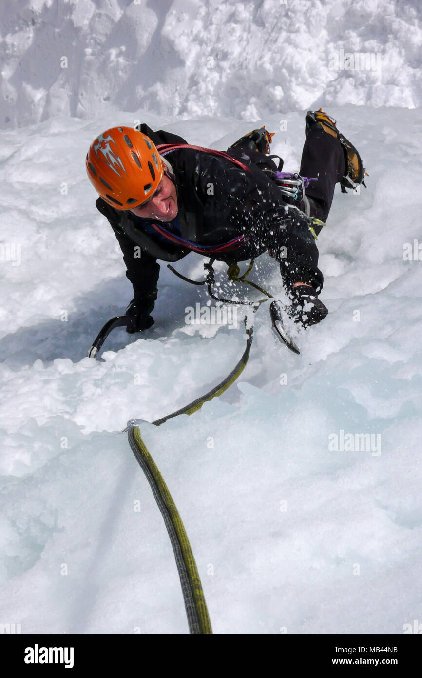 male ice climber on a steep frozen waterfall on a beautiful winter day ...