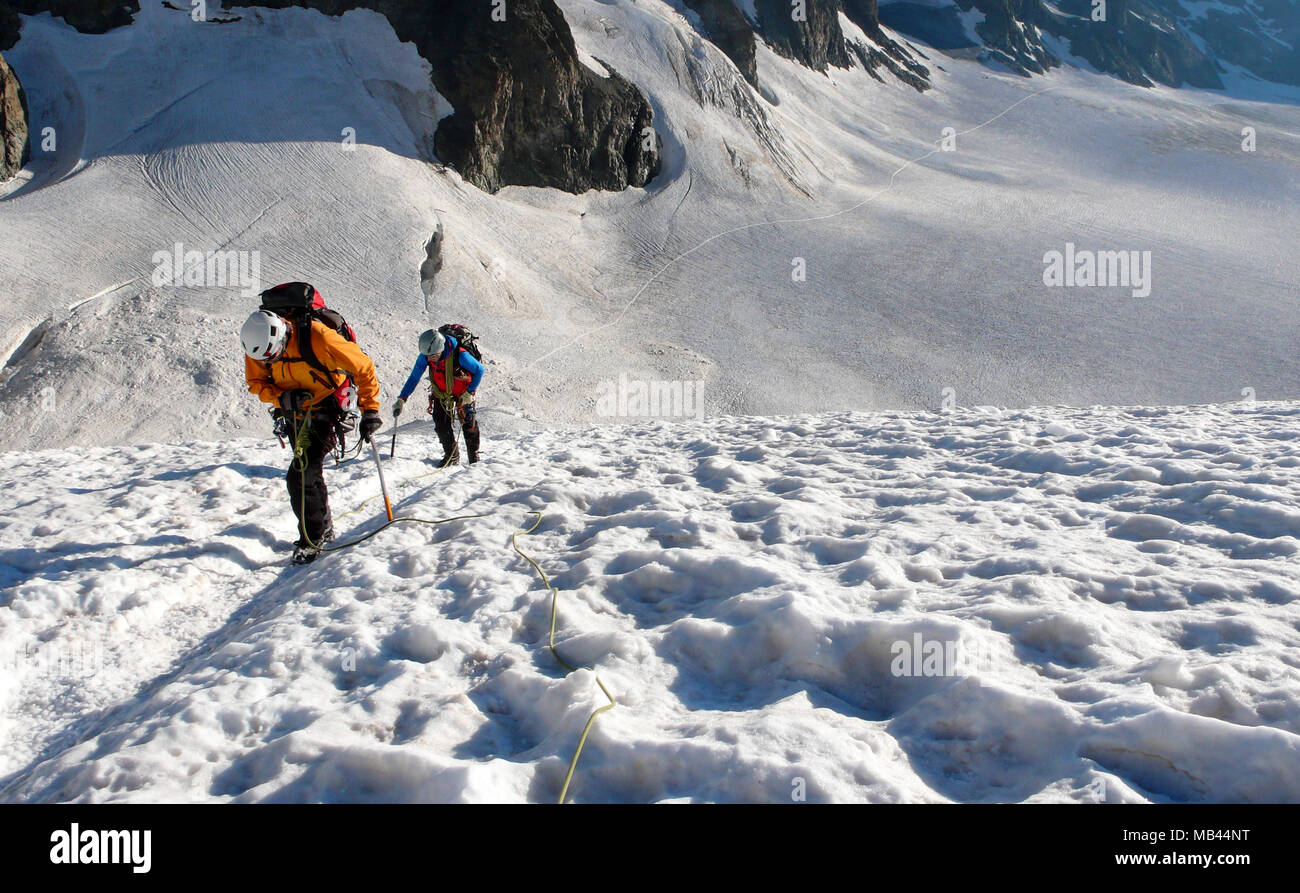 mountain guide and client heading up a glacier towards a high alpine ...