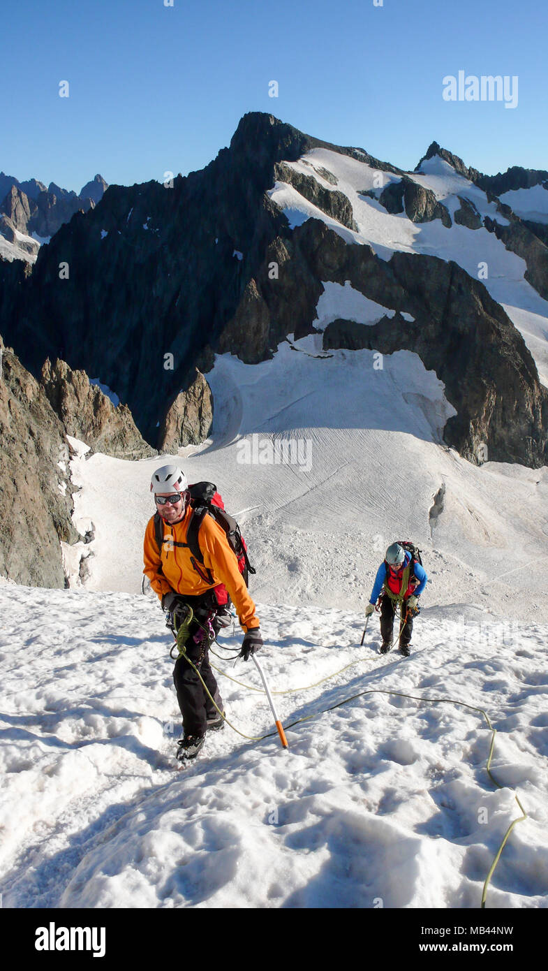 mountain guide and client heading up a glacier towards a high alpine ...