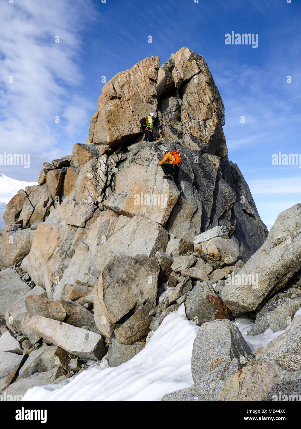 mountain guide and a male client on a rocky ridge heading towards a ...