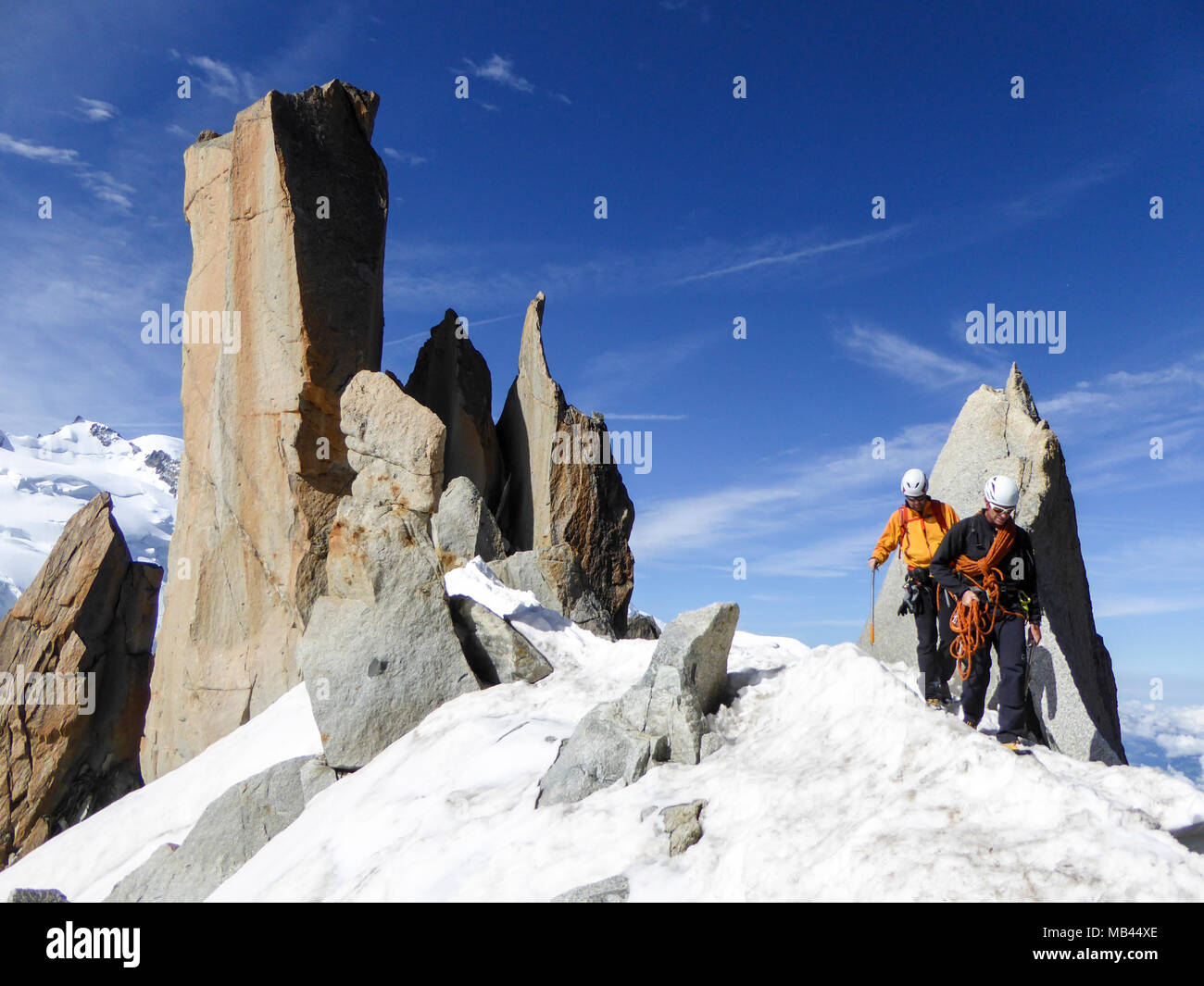 mountain guide and a male client on a rocky ridge heading towards a ...