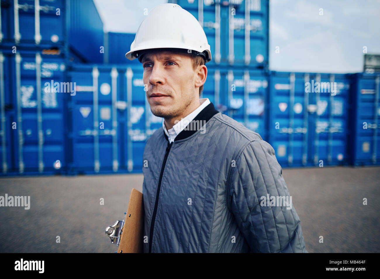 Dock foreman wearing a hardhat standing alone on a large commercial ...