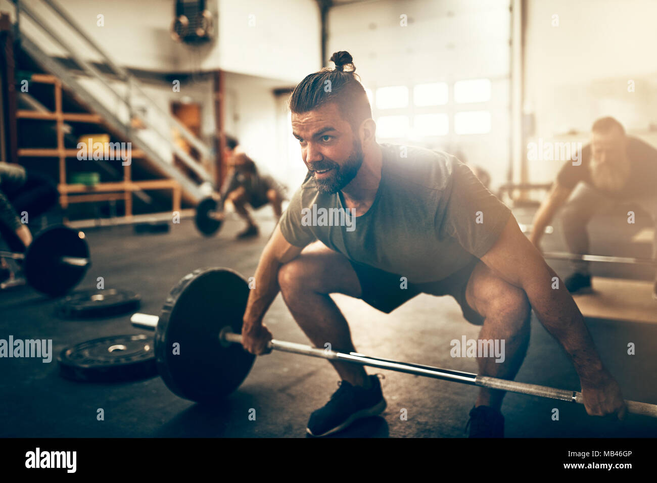 Fit young man in sportswear focused on lifting heavy weights while ...