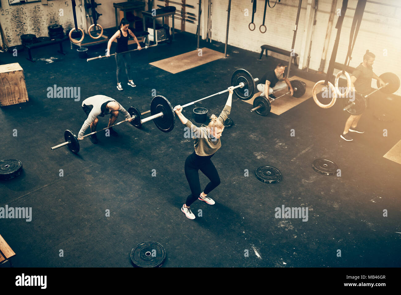 High angle of a group of fit people lifting weights together during an ...