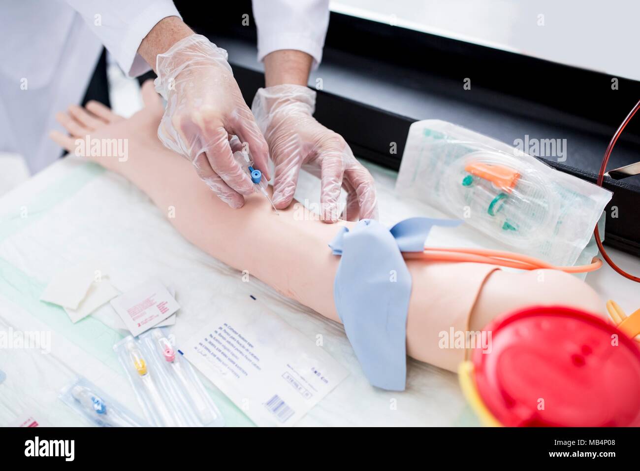 Doctor practising inserting an IV (intravenous) line on a training ...