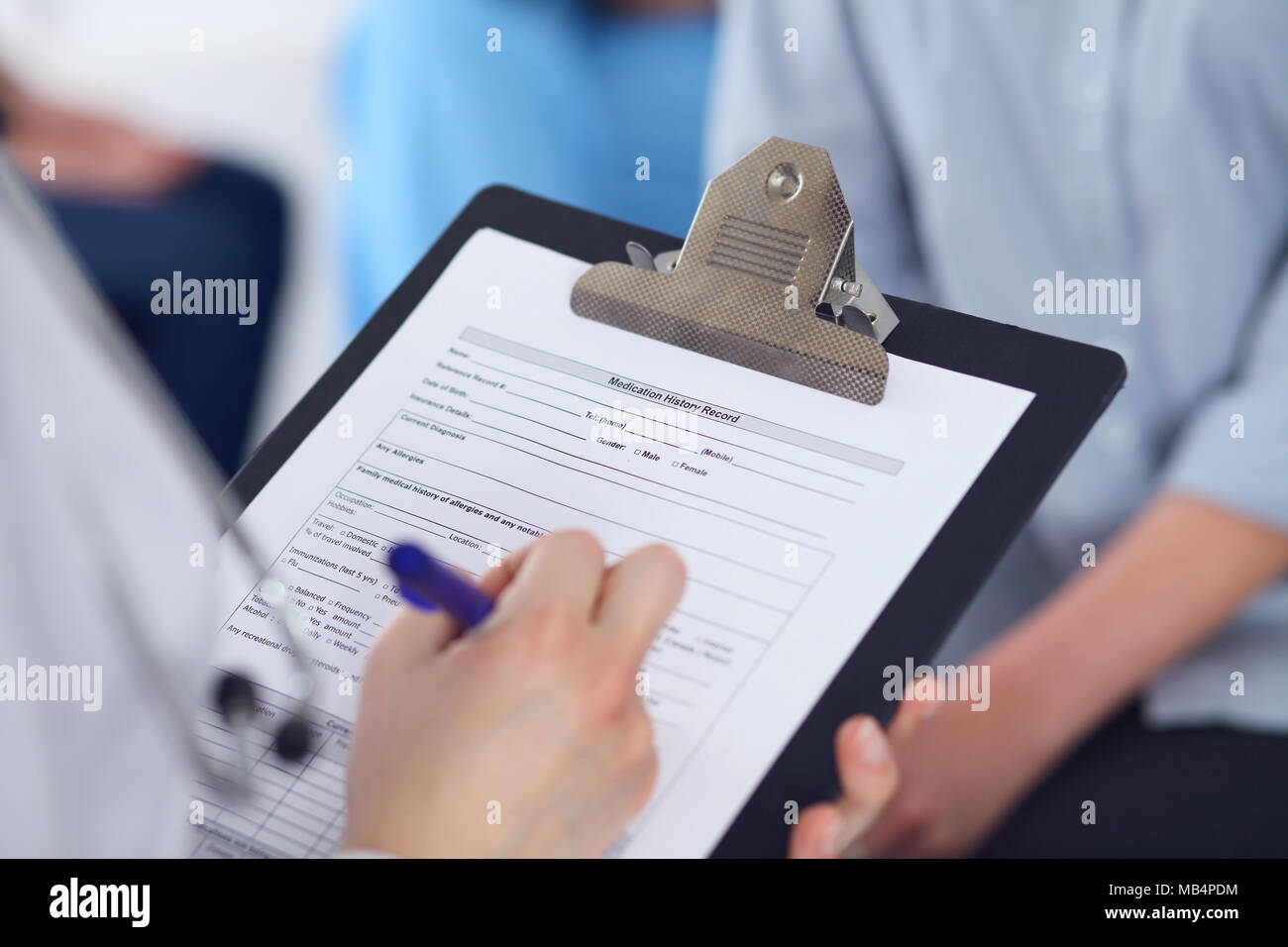 Close Up of a female doctor filling out application form while talking ...