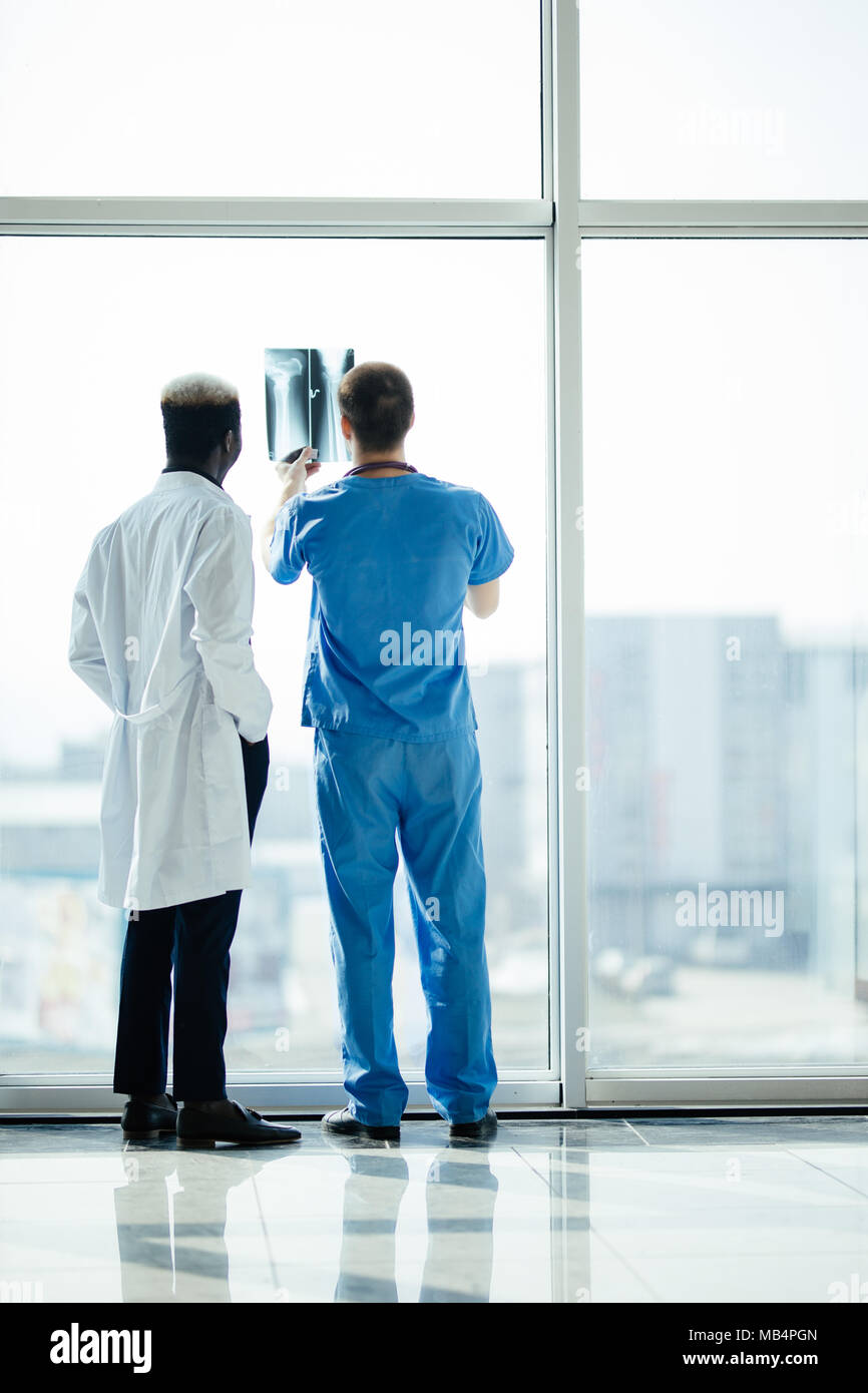 Back of two doctors checking X-rays on modern office background Stock ...
