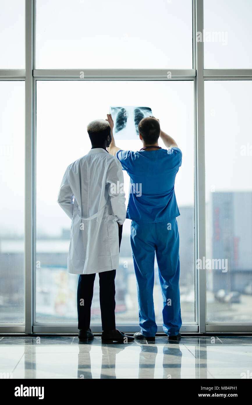 Back of two doctors checking X-rays on modern office background Stock ...