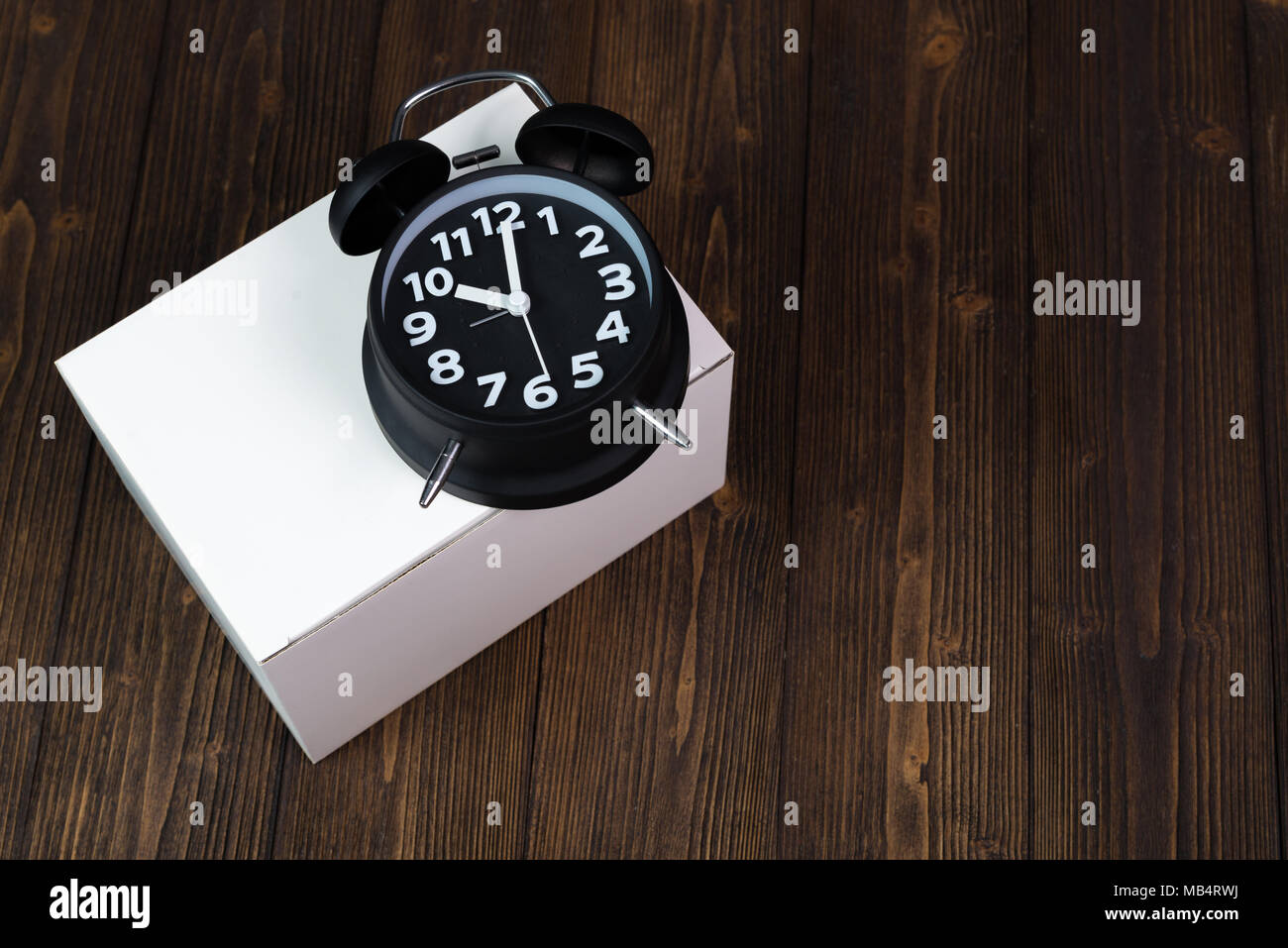 Vintage black alarm clock with white packaging gift box on dark wood ...