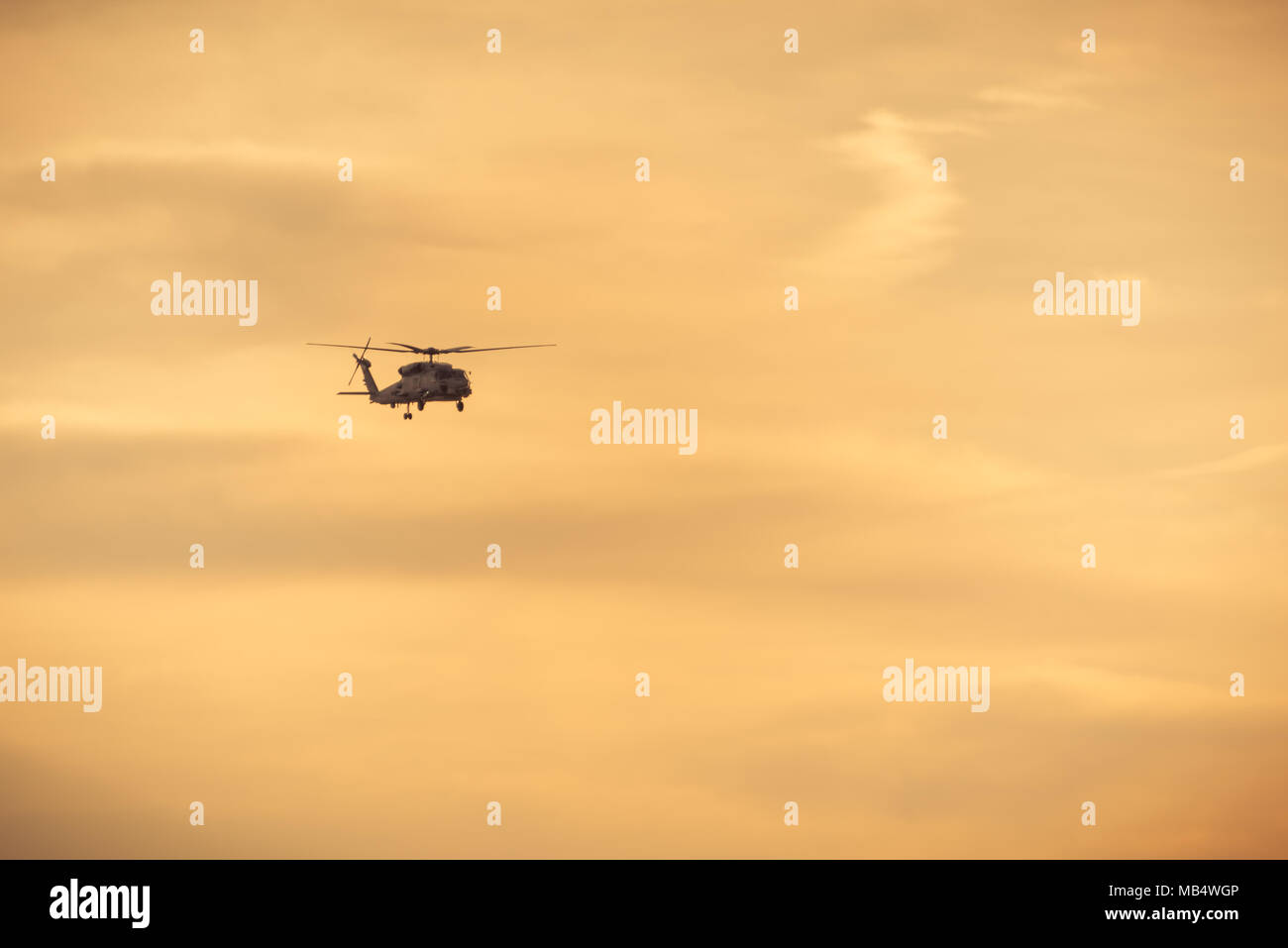Helicopter flying against amber sky at sunset Stock Photo - Alamy