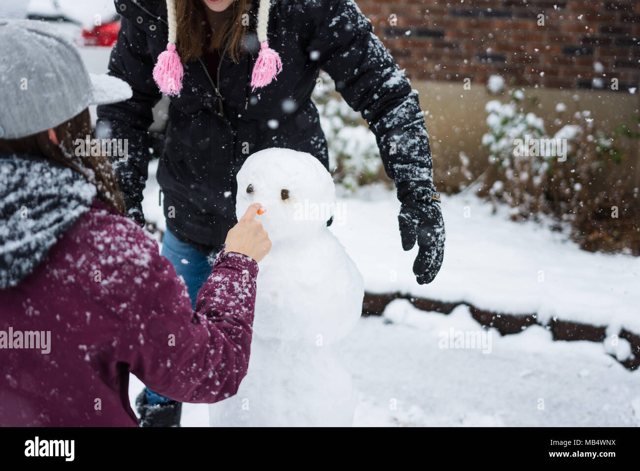 Snow fun building a snowman in a snow storm Stock Photo - Alamy