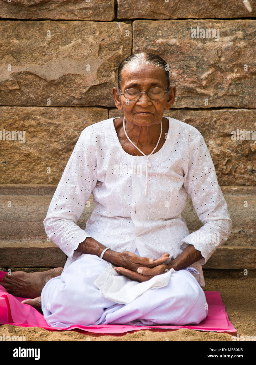 Vertical portrait of an old lady meditating at Jaya Sri Maha Bodhi in ...