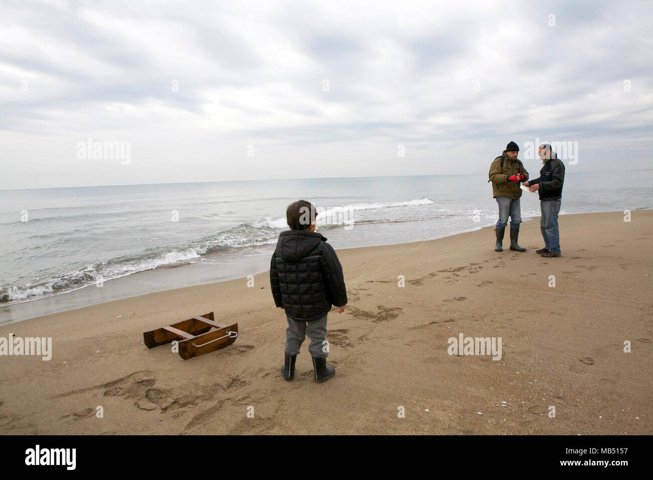 Little boy staring in wonder at fishermen on the beach, Lavinio, Italy ...