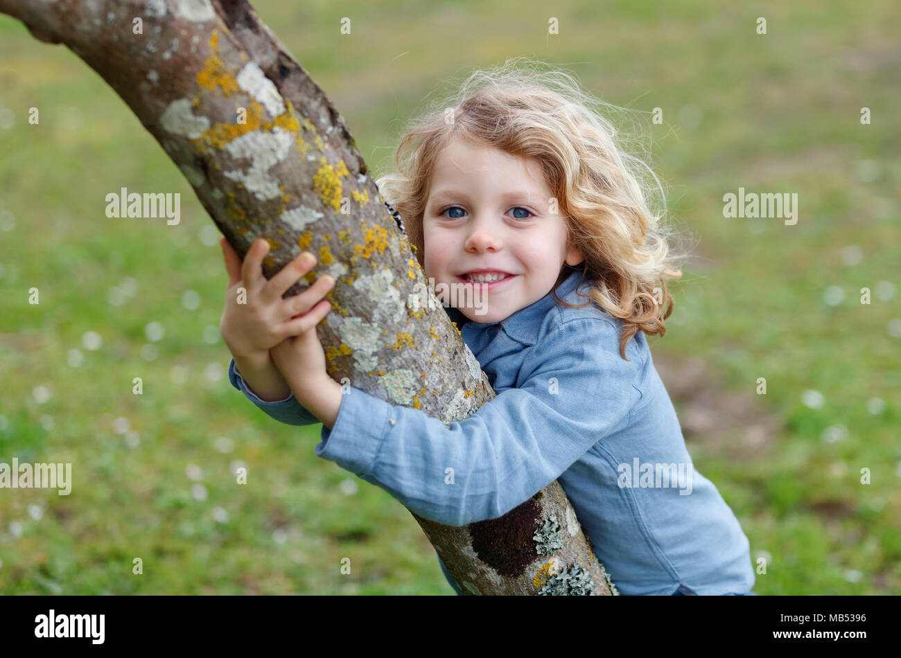 Happy small child with long blond hair hugging a tree Stock Photo - Alamy