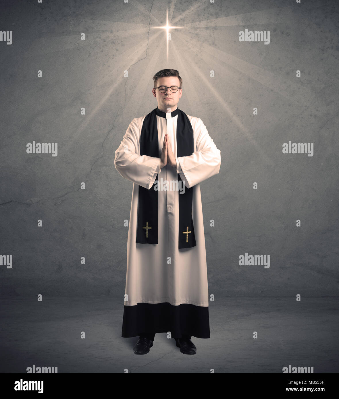 A young male priest in black and white giving his blessing in front of ...
