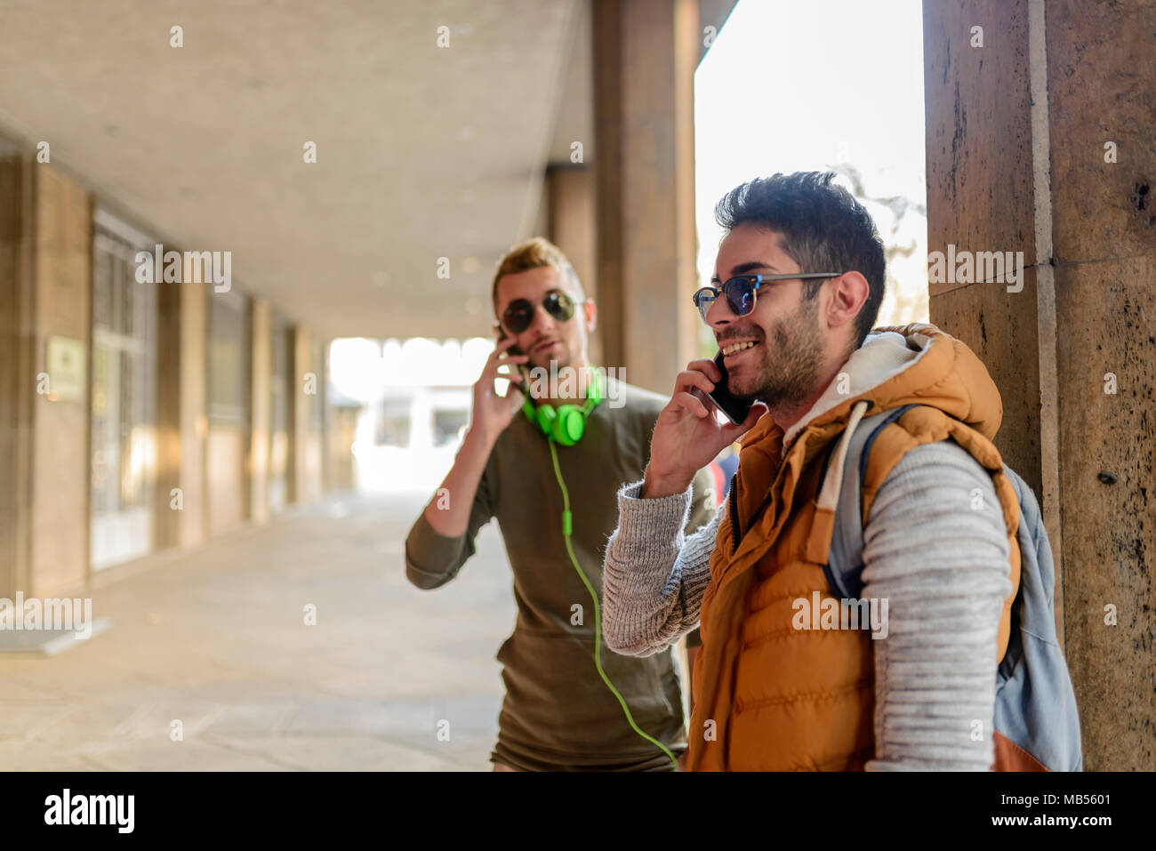 Two young men talking on the phone in city passage Stock Photo - Alamy