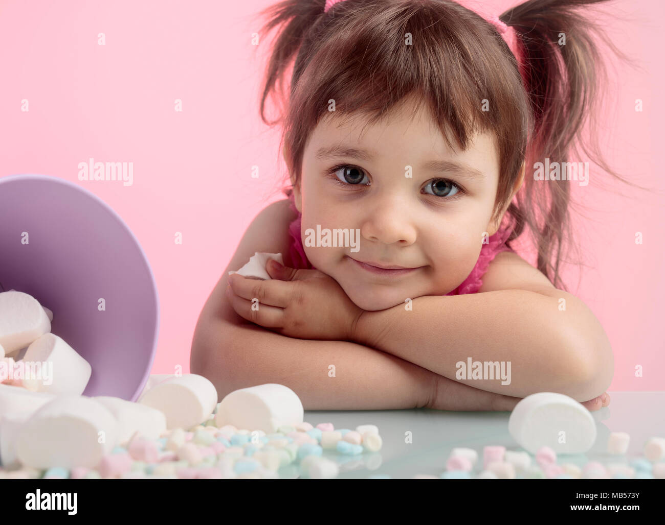 Portrait of a cute little girl with marshmallow, isolated over pink ...