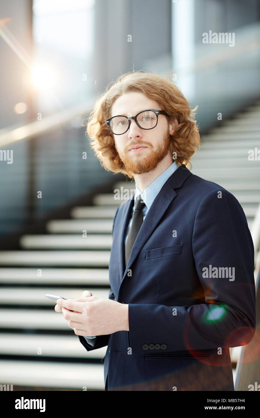 Bearded employee in suit and eyeglasses looking at camera in airport ...