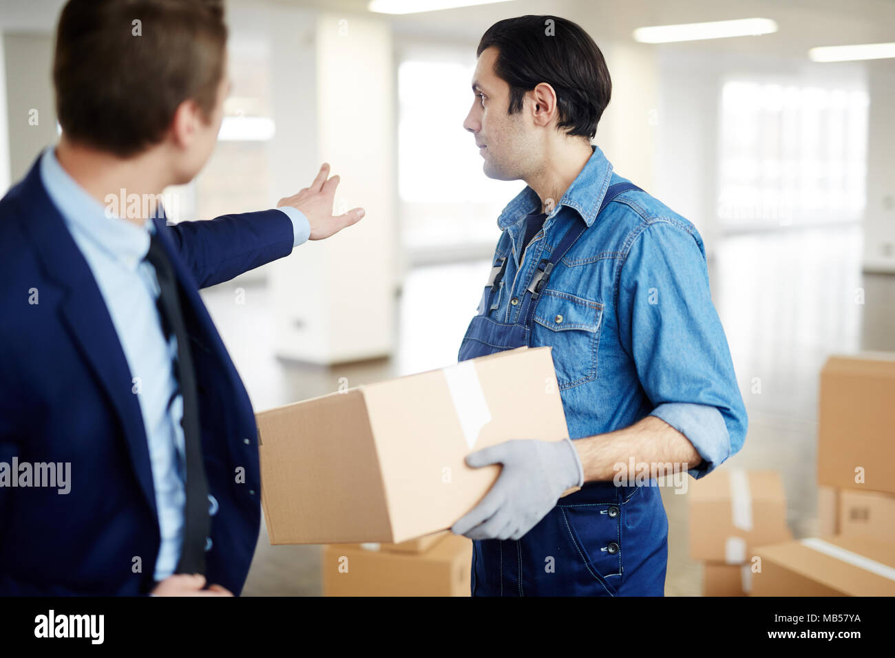 Businessman showing worker where to put box with supplies during ...