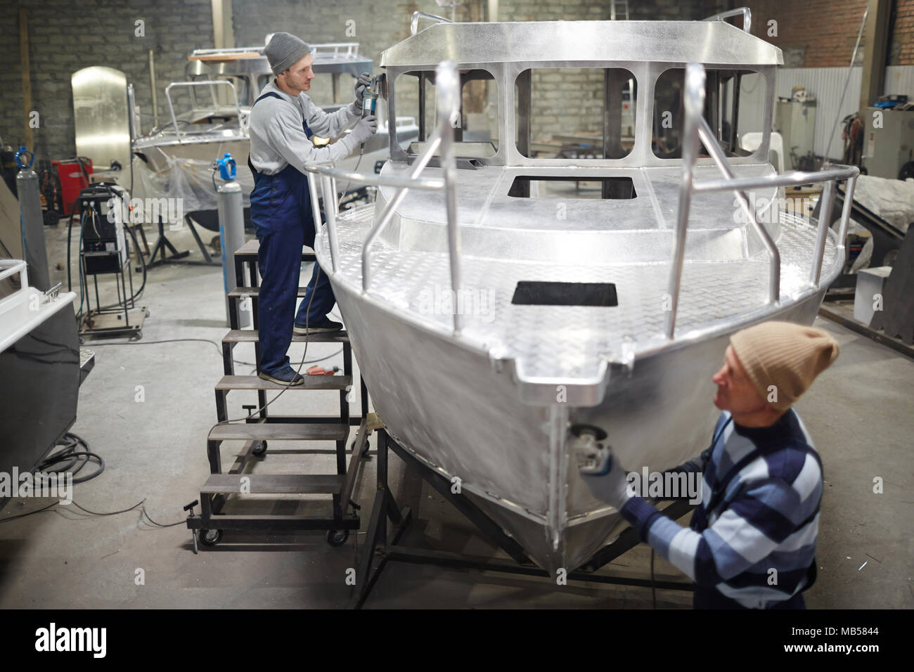 Modern shipbuilding engineers working over new boat in production ...