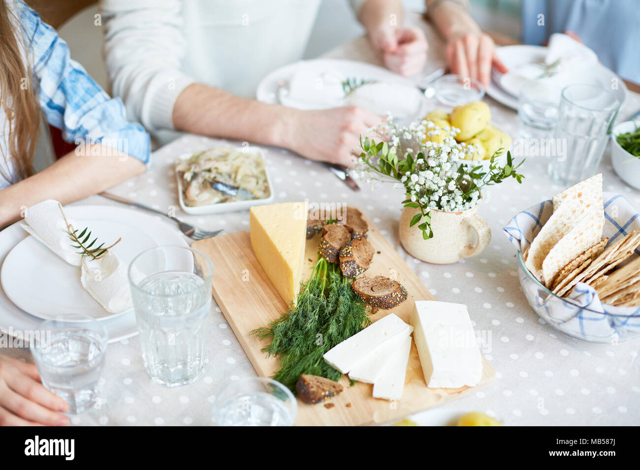 Assortment of healthy food on served table and group of friends sitting ...