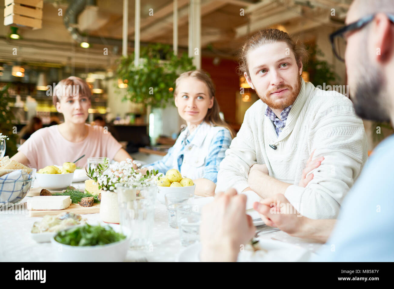 Three people listening to their friend story by dinner while having ...