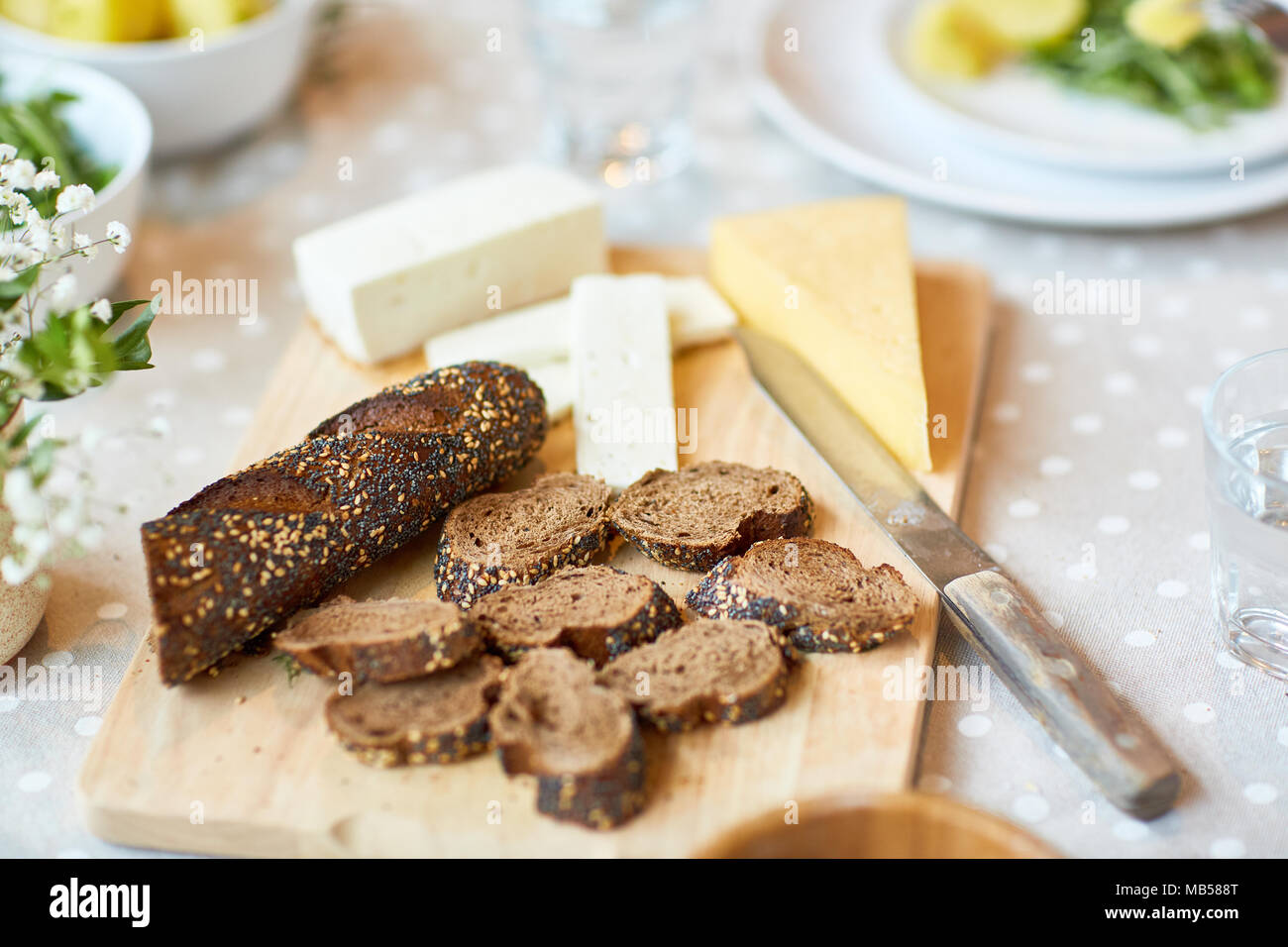 Several slices of fresh rye bread and cheese on wooden board among ...