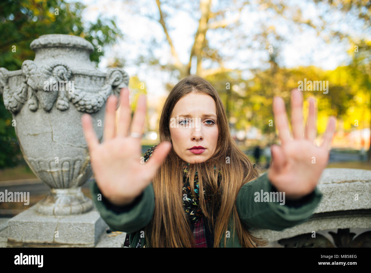 Attractive young woman in park is displeased and making a stop sign ...