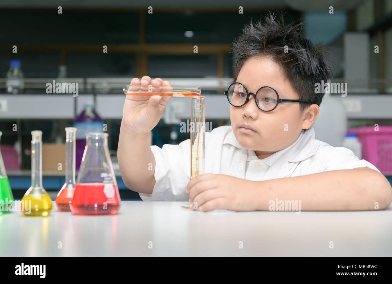 scientist boy in lab coat making experiment with test tube in chemical ...