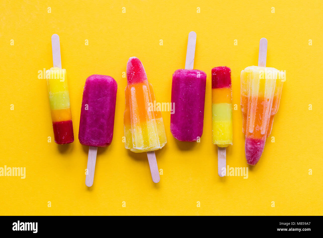 A selection of bright summer ice lollies on a yellow background Stock ...