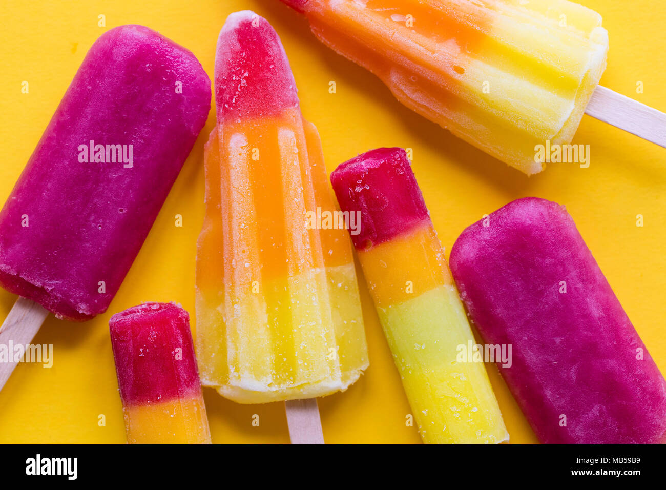 A selection of bright summer ice lollies on a yellow background Stock ...