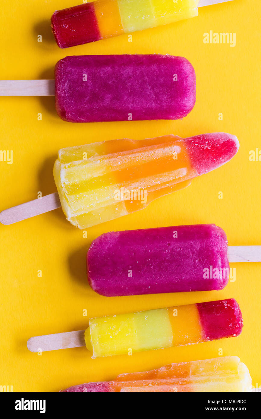 A selection of bright summer ice lollies on a yellow background Stock ...