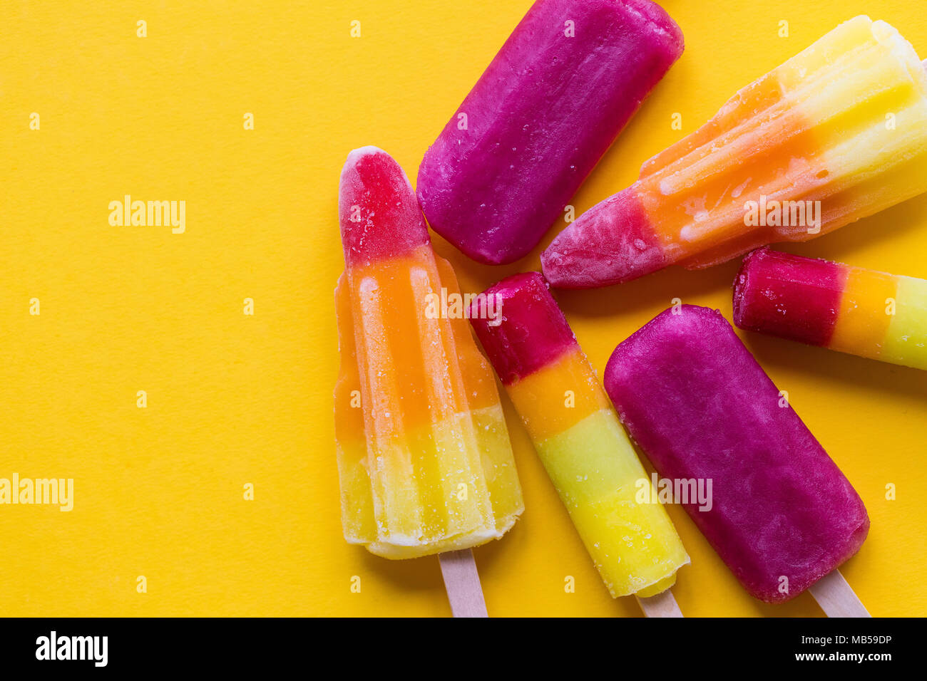 A selection of bright summer ice lollies on a yellow background Stock ...