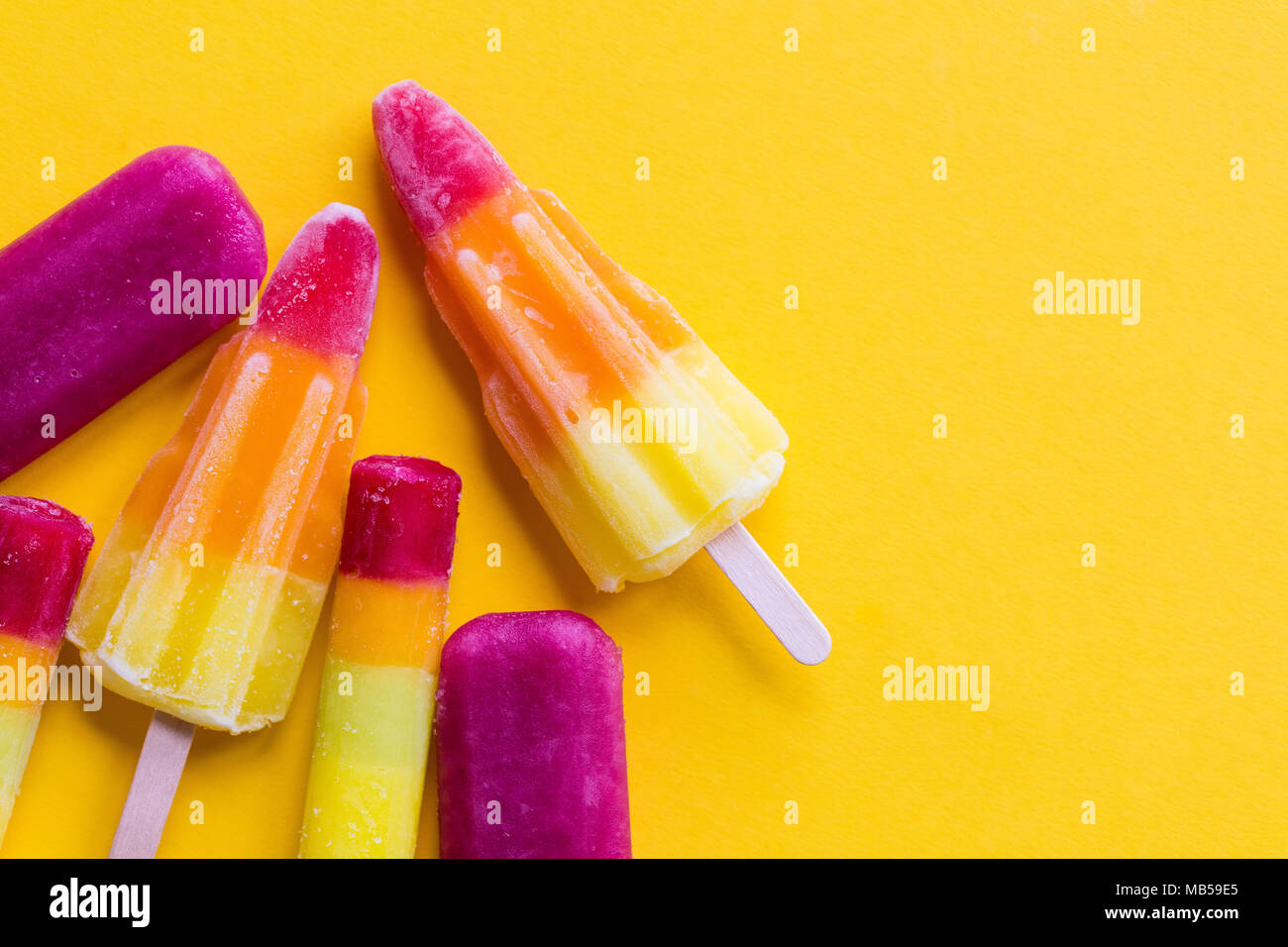 A selection of bright summer ice lollies on a yellow background Stock ...