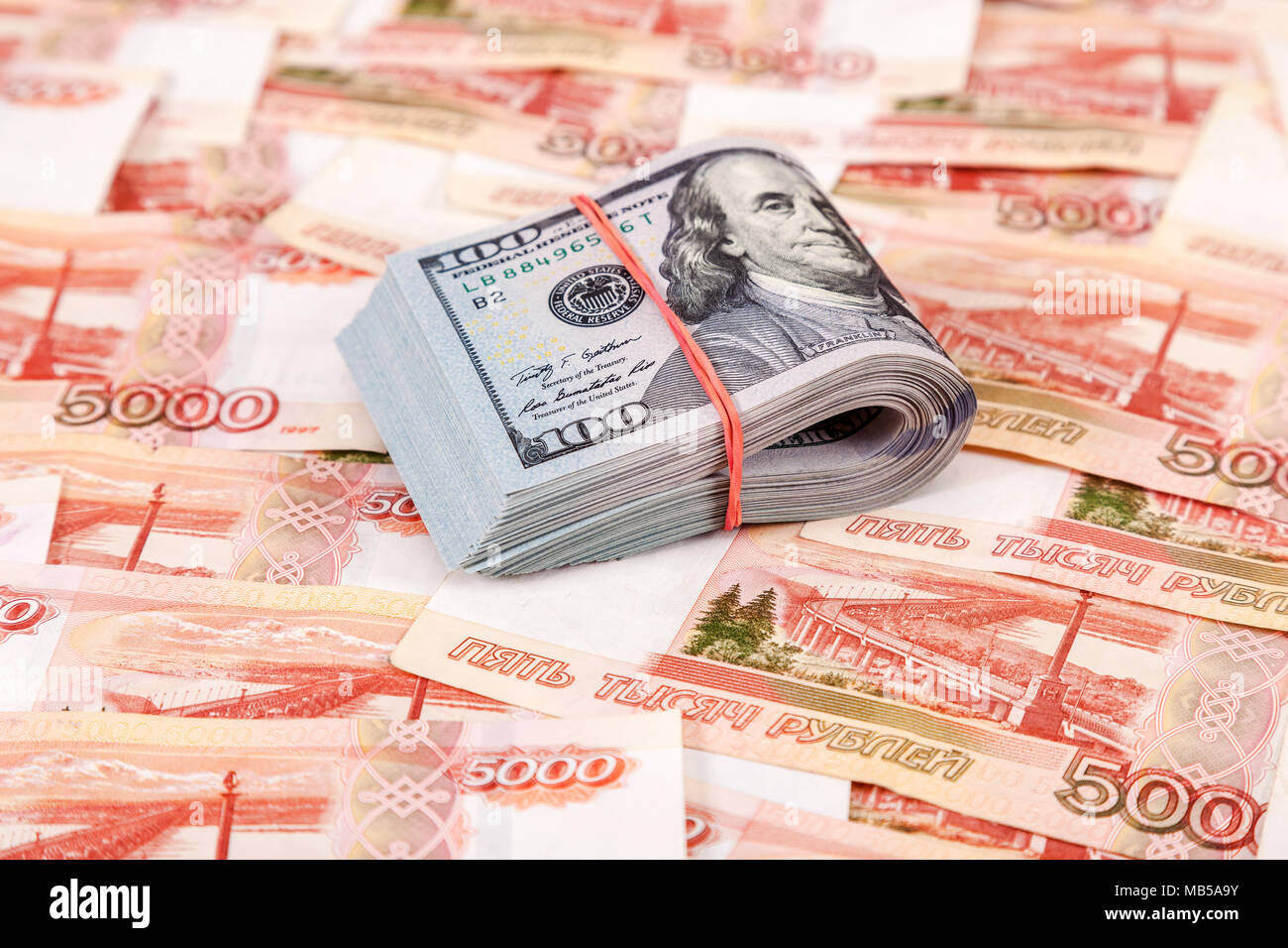 Folded dollar bills wrapped by rubber band over banknotes of russian ...