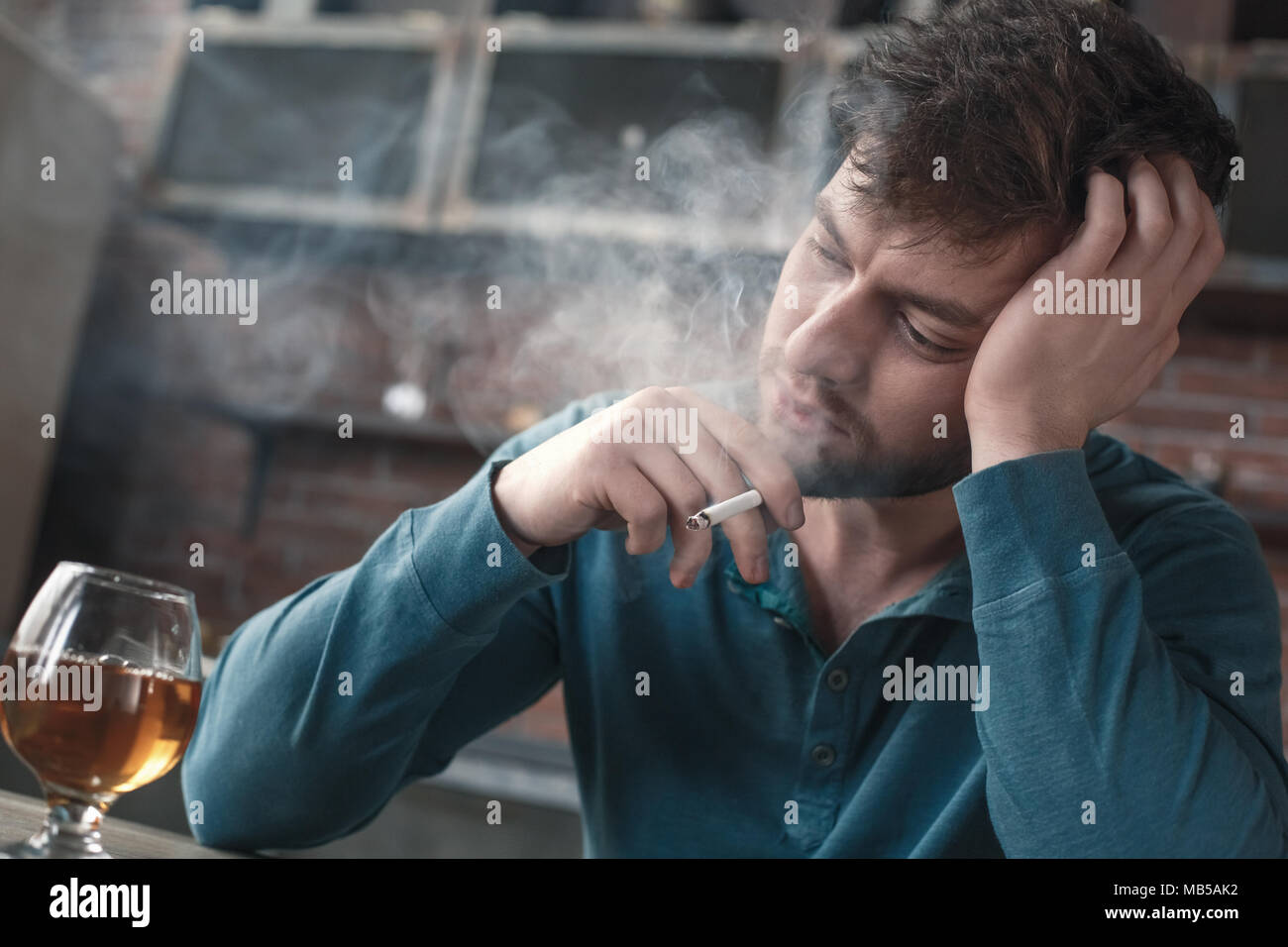Young man smoking addiction problems sitting at table smoking cigarette ...