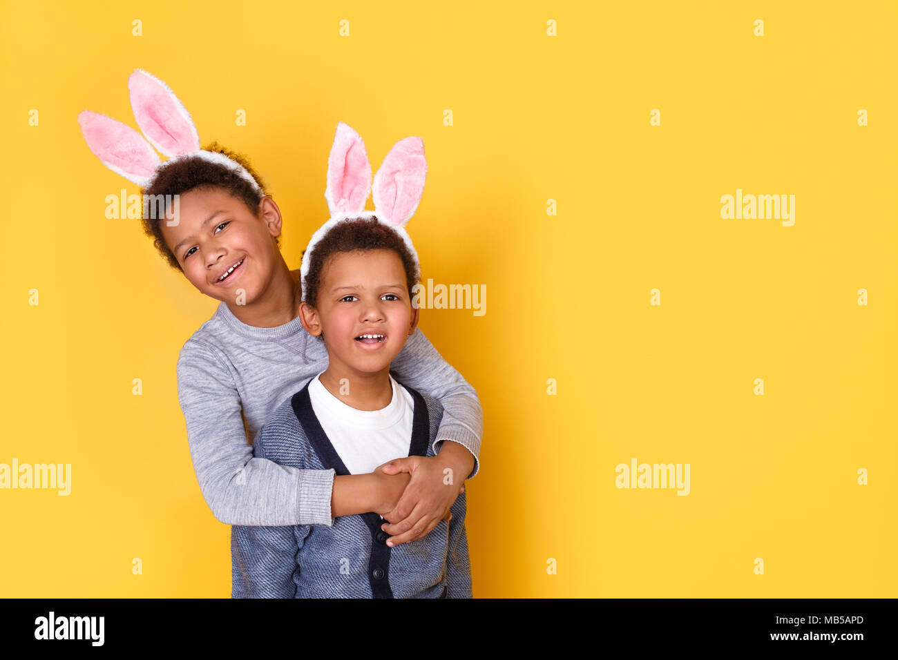 Two brothers wearing bunny ears studio isolated on yellow background ...