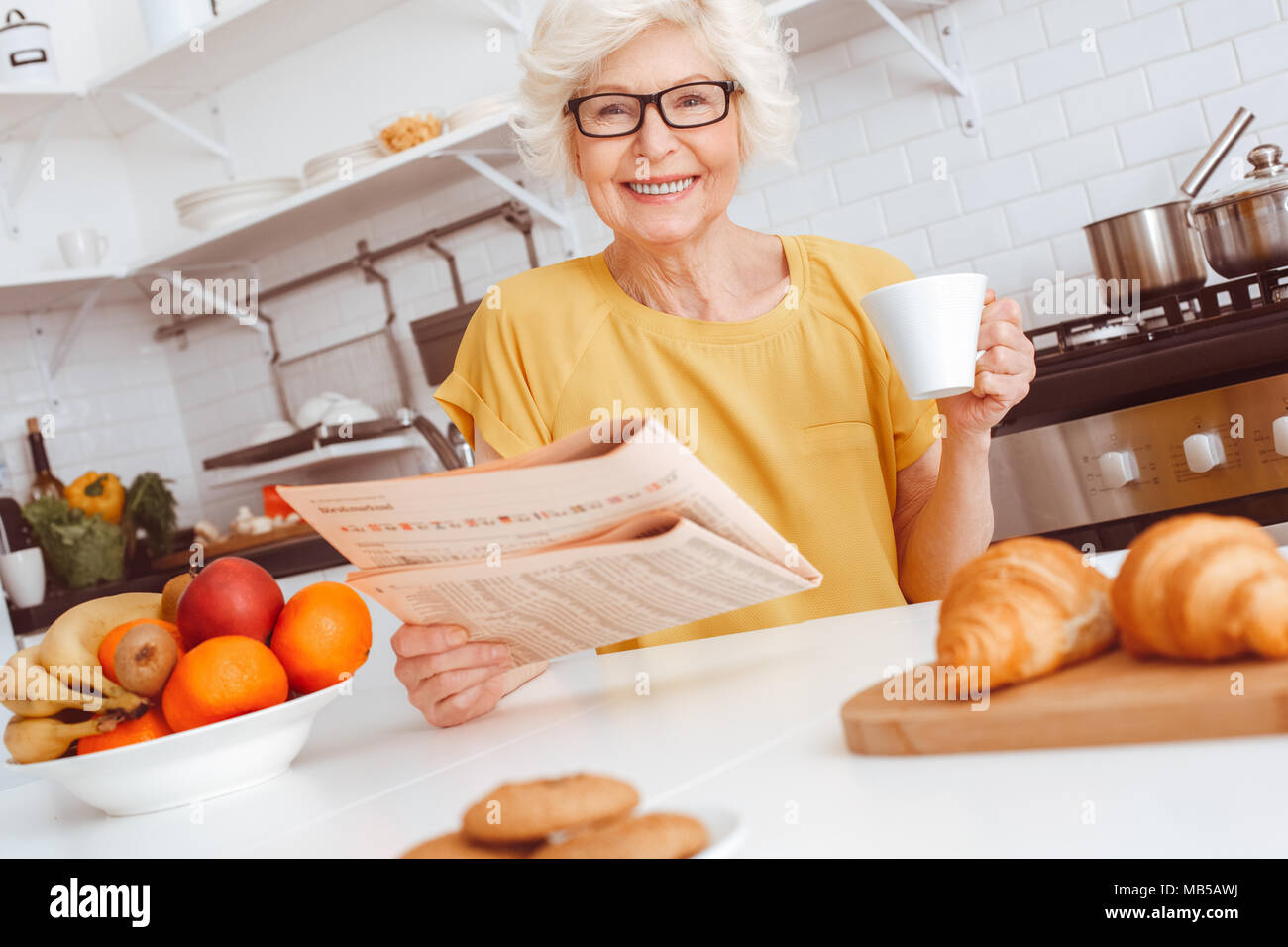 Grandmother drinks coffee in the morning and reads the newspaper ...