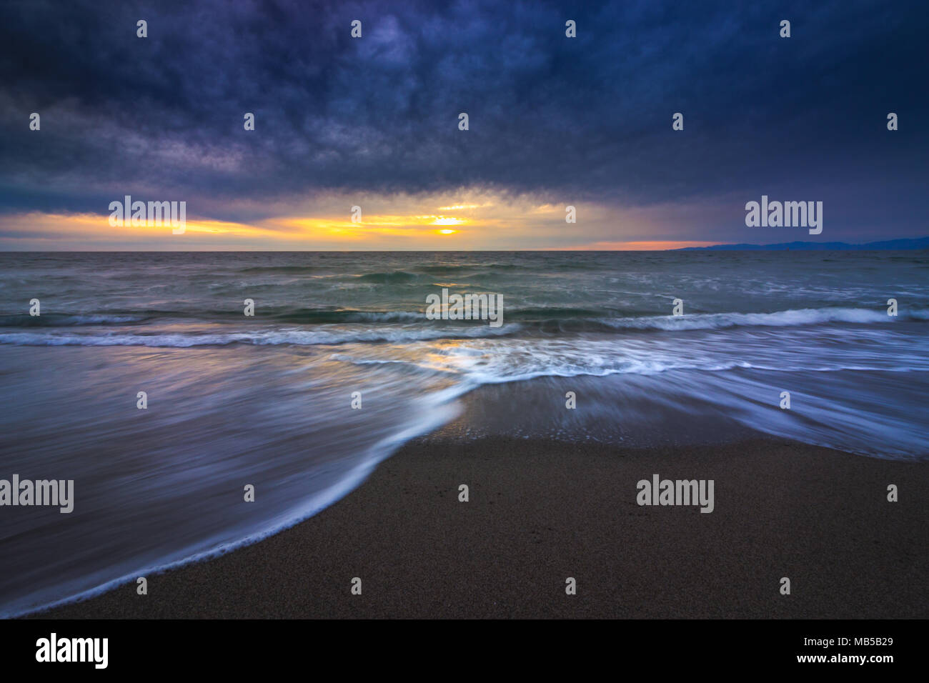 Long-exposure photograph of silky smooth waves washing onto the sandy ...