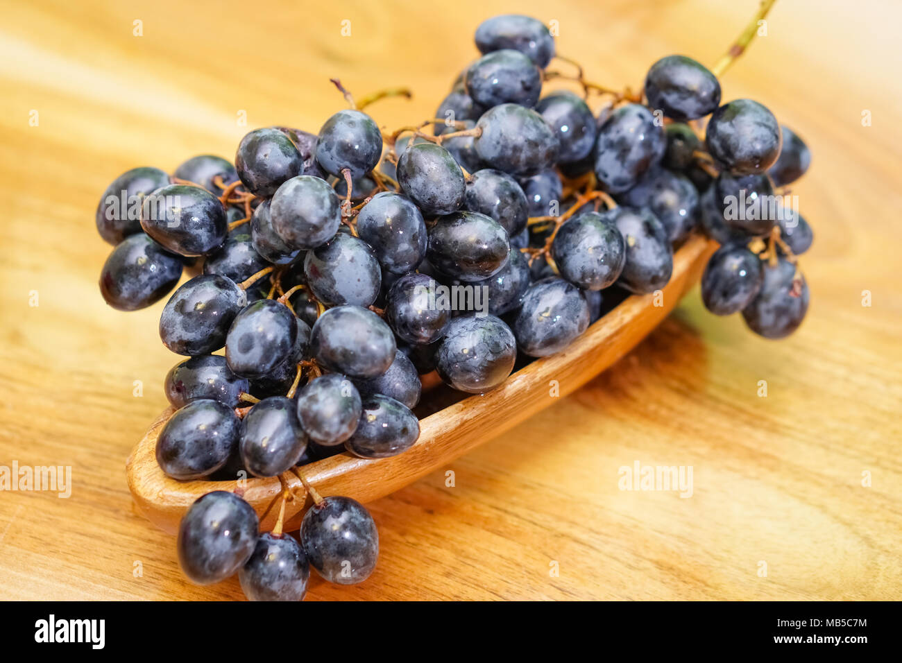 Fresh grapes in wooden bowl on wooden table Stock Photo - Alamy