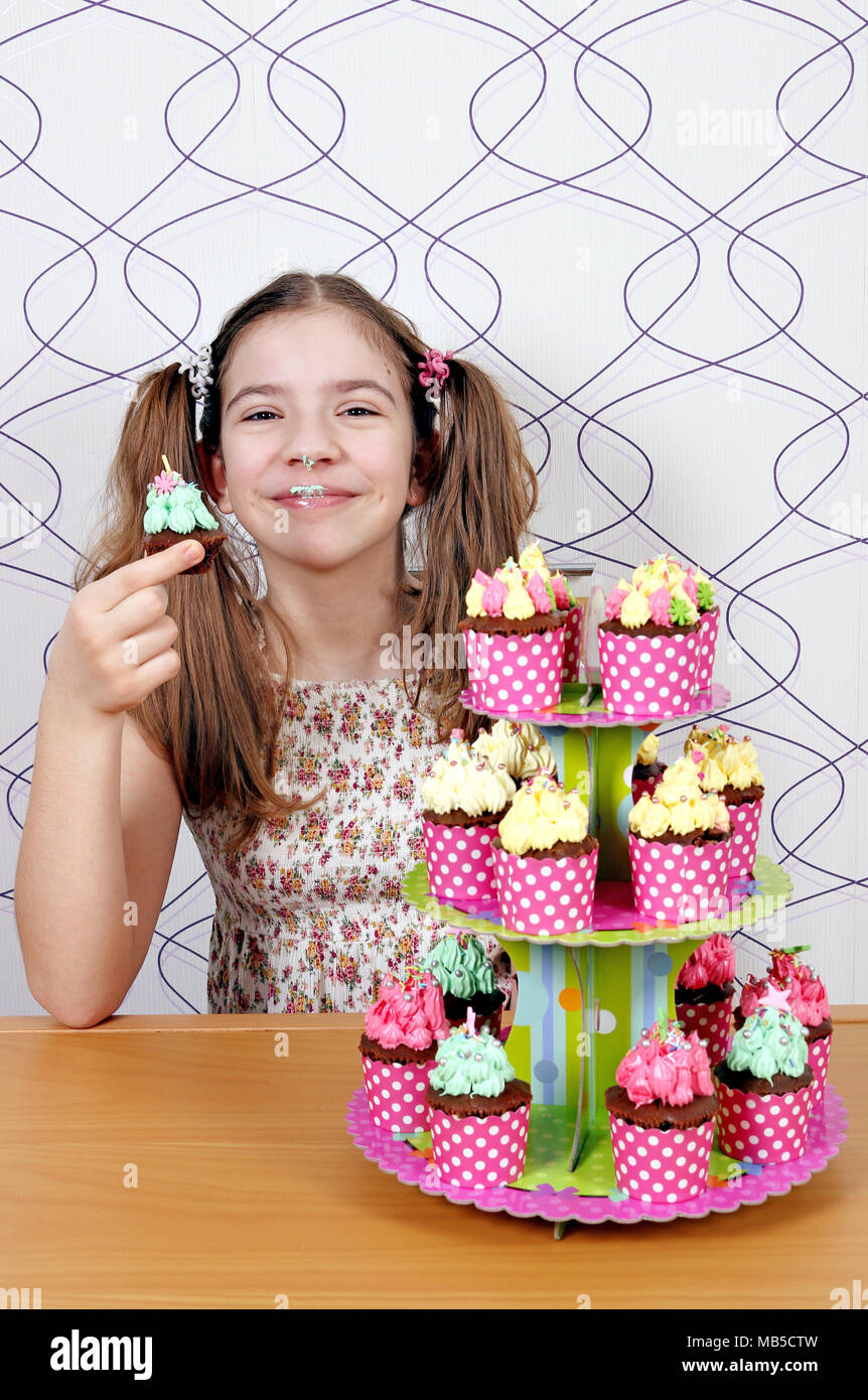 Happy little girl with besmear face and muffins cakes Stock Photo - Alamy