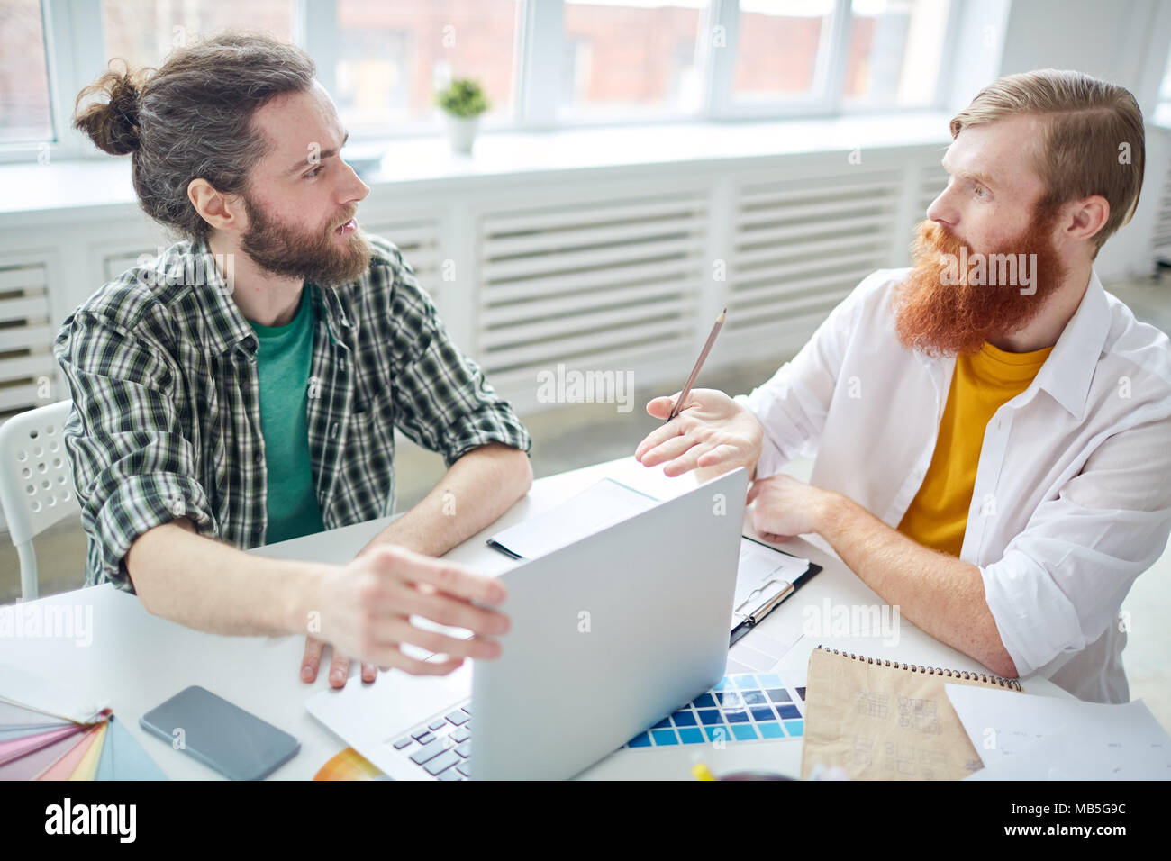 Male designers thinking about new ideas and using laptop at office ...
